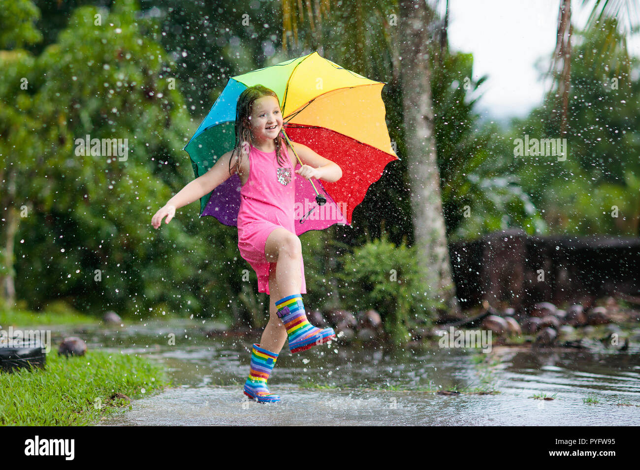 Kid playing out in the rain. Children with umbrella and rain boots play ...