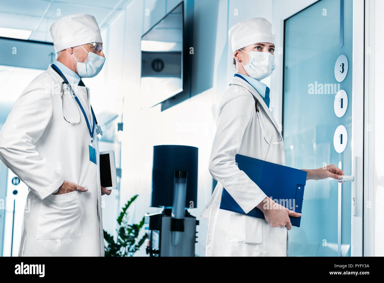 female doctor with clipboard opening door while her male colleague ...