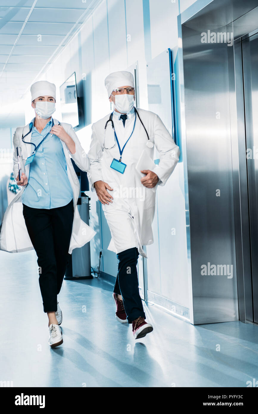 male and female doctors with digital tablet and clipboard running in ...