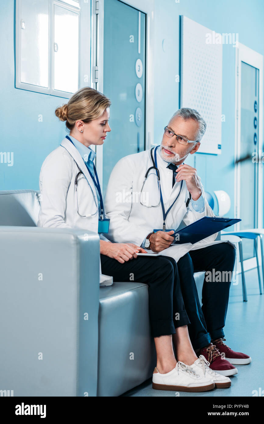 male and female doctors talking on couch in hospital corridor Stock ...
