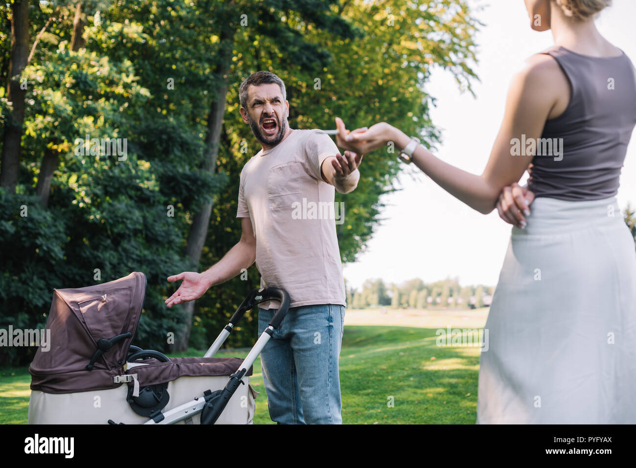 cropped image of mother smoking cigarette near baby carriage in park ...
