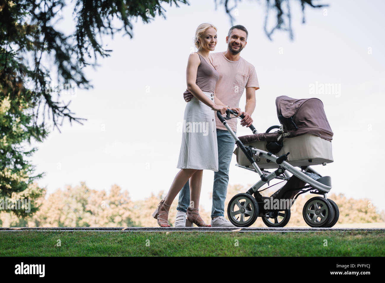 happy parents walking with baby carriage in park Stock Photo - Alamy