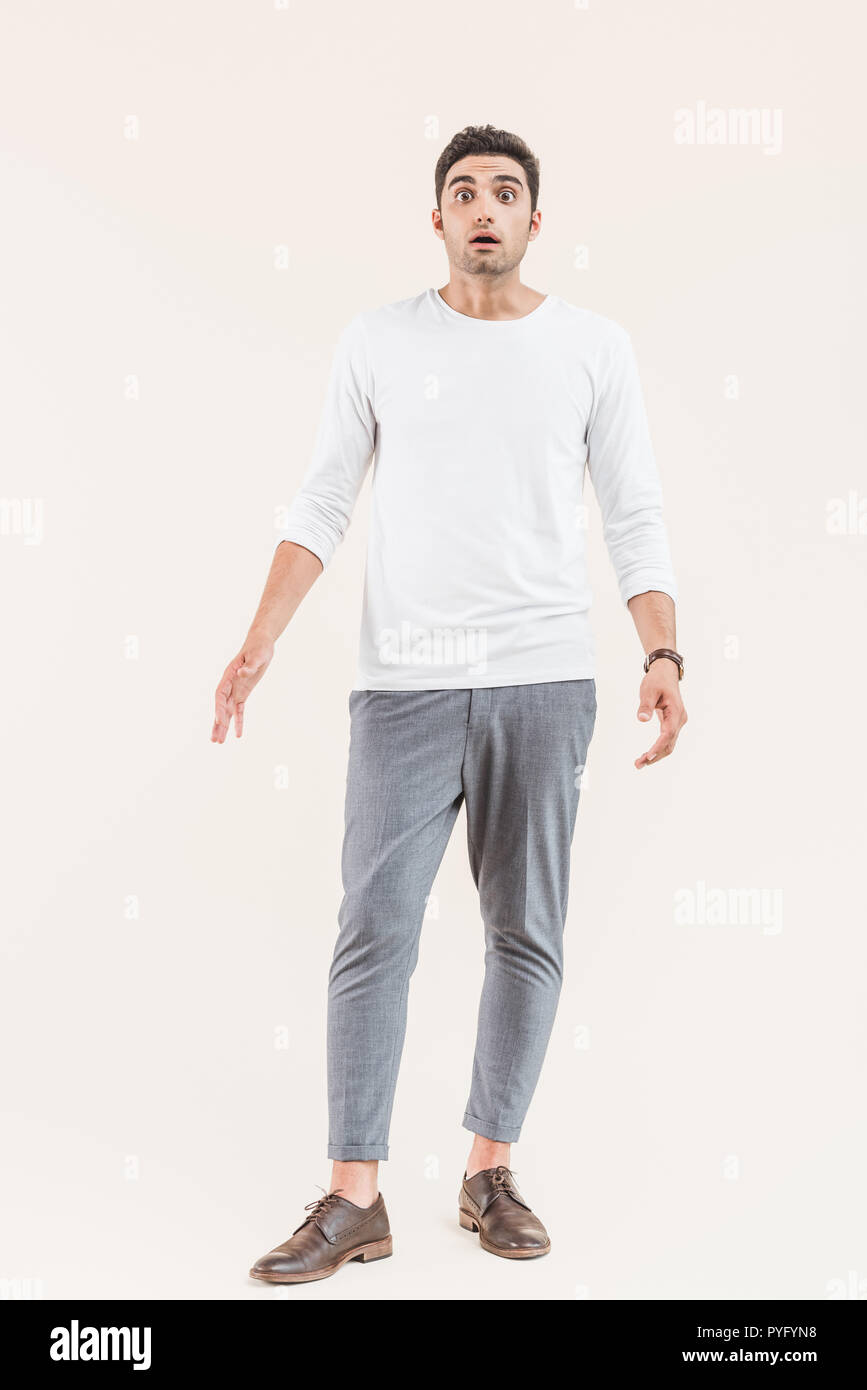 full length view of shocked young man looking at camera isolated on ...