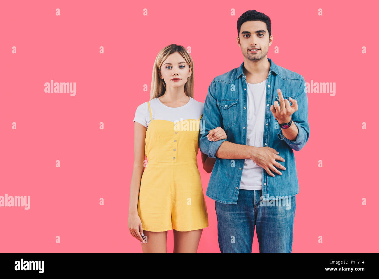 handsome young man showing middle finger while his girlfriend standing ...