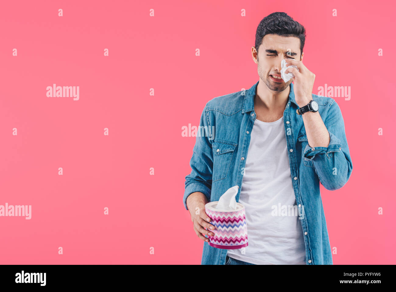 sad young man with tissue box crying and wiping tears isolated on pink ...