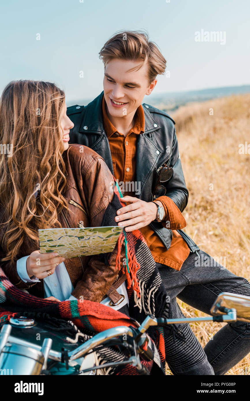 young girlfriend holding map near handsome boyfriend sitting on ...
