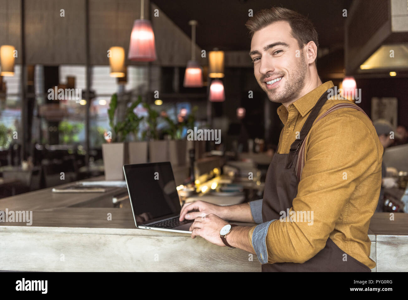 handsome young waiter using laptop a bar counter in cafe Stock Photo ...