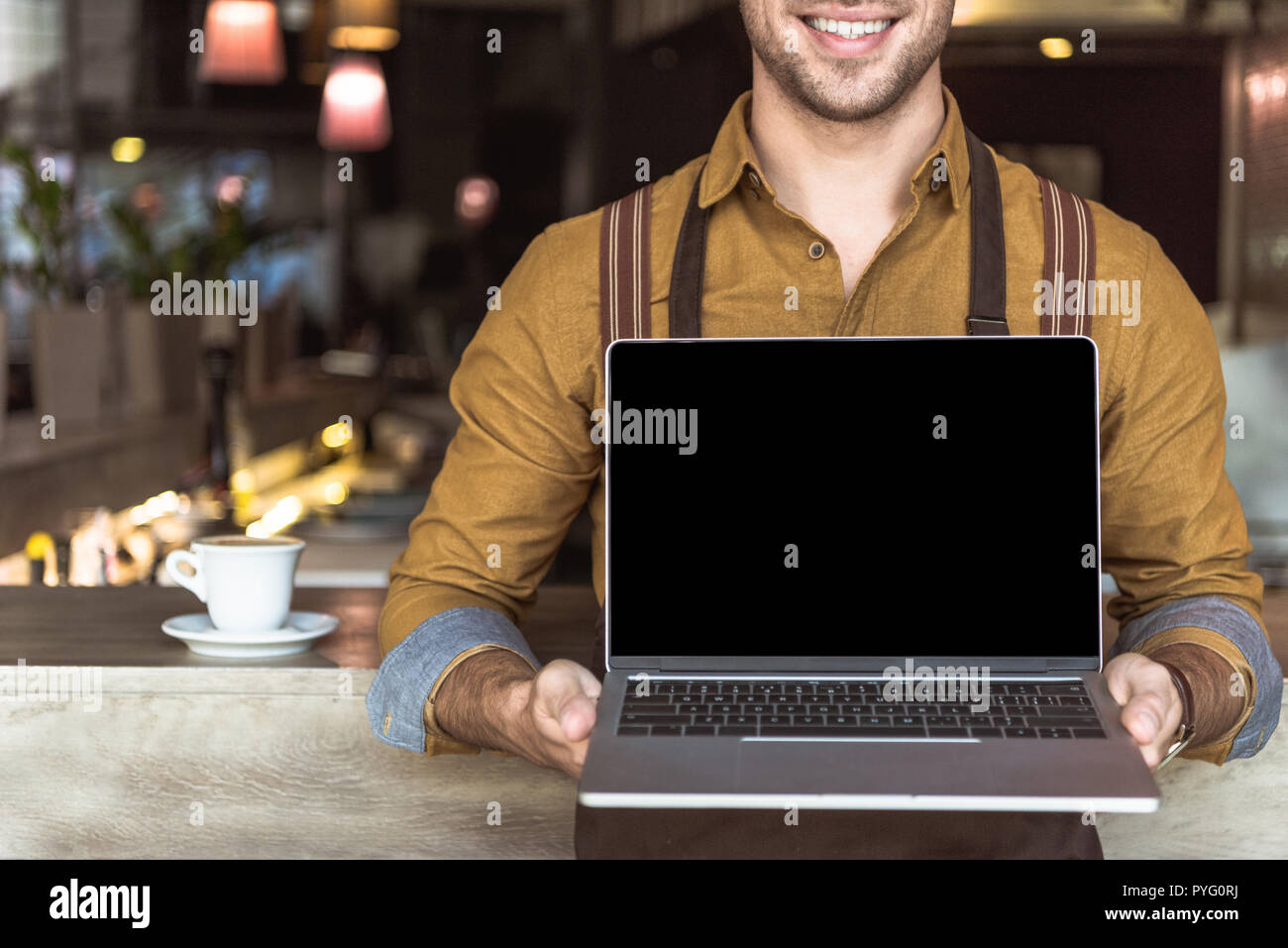 happy young waiter holding laptop with blank screen in cafe Stock Photo ...