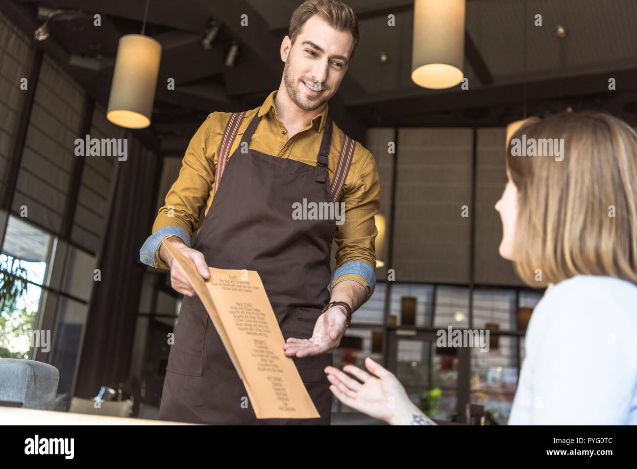 happy young waiter showing menu list to female customer in cafe Stock ...