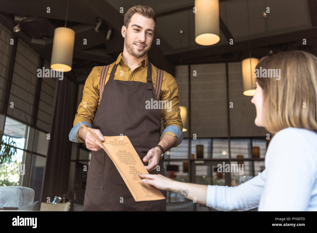 handsome young waiter showing menu list to female customer in cafe ...