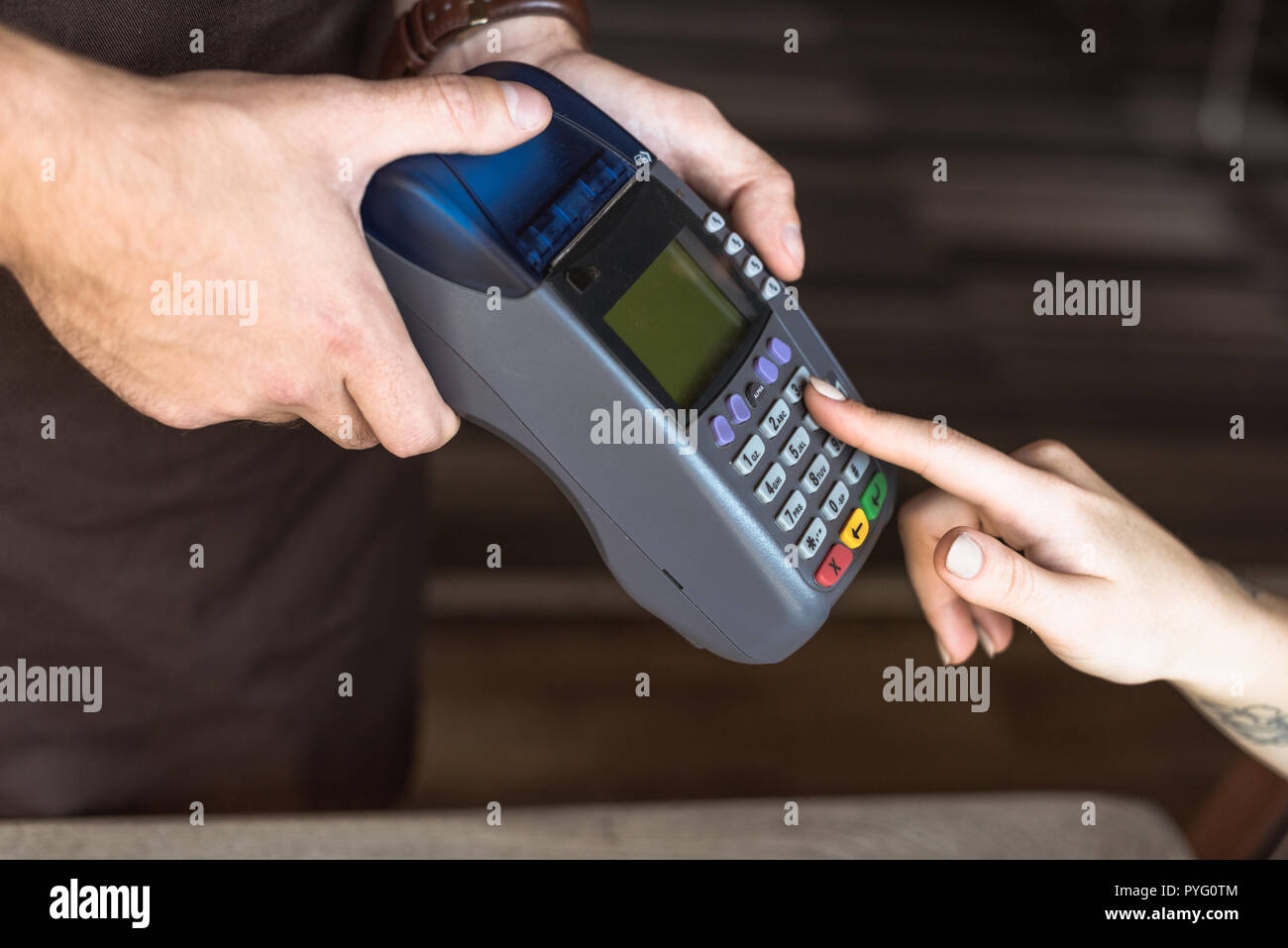 cropped shot of waiter holding payment terminal while customer entering ...