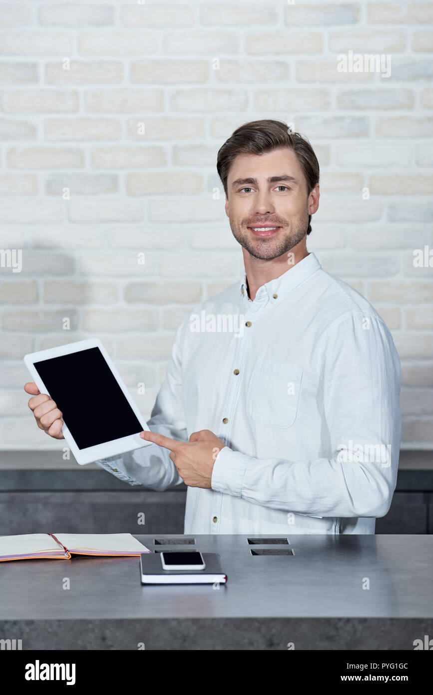 handsome young salesman holding digital tablet with blank screen and ...