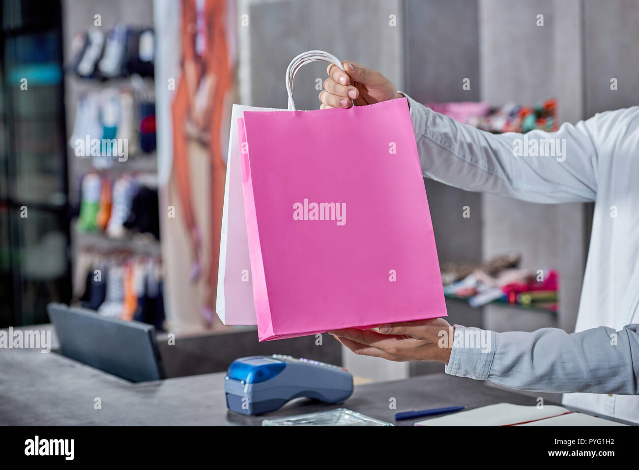 partial view of young salesman holding paper bags in shop Stock Photo ...