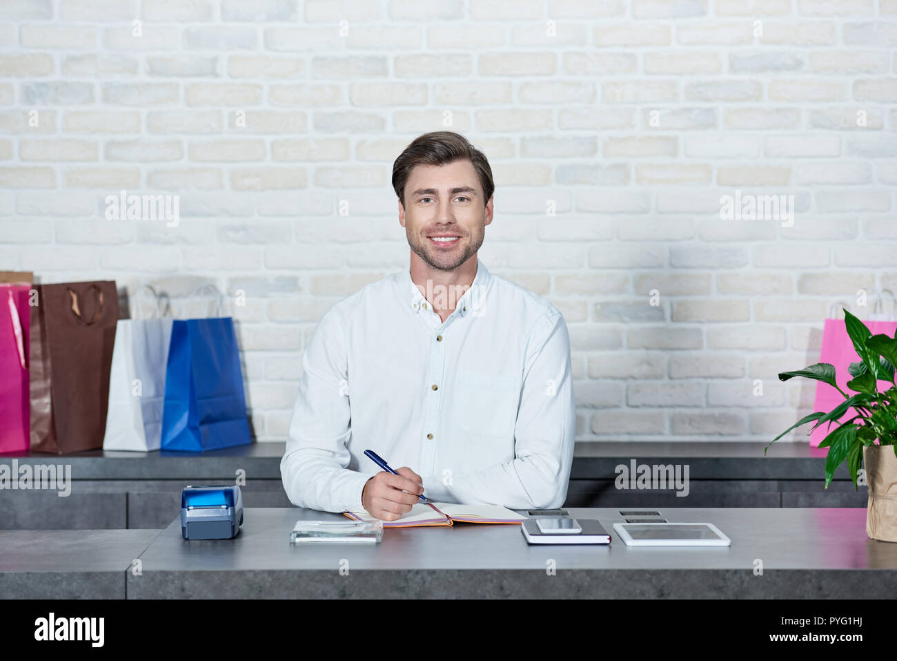 handsome young salesman smiling at camera while working in store Stock ...