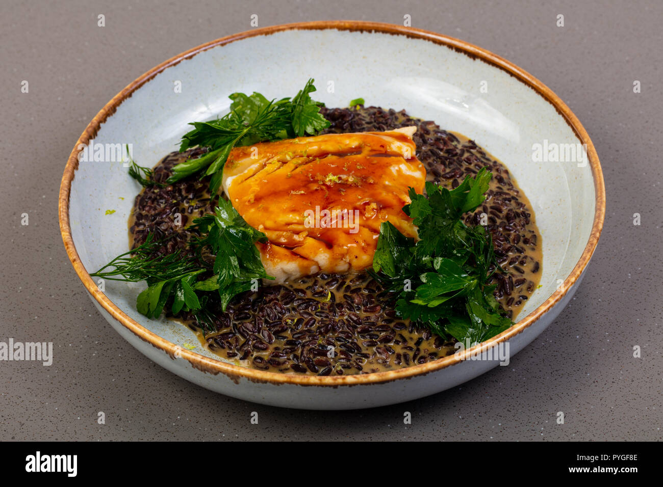 Cod fish with black rice Stock Photo - Alamy