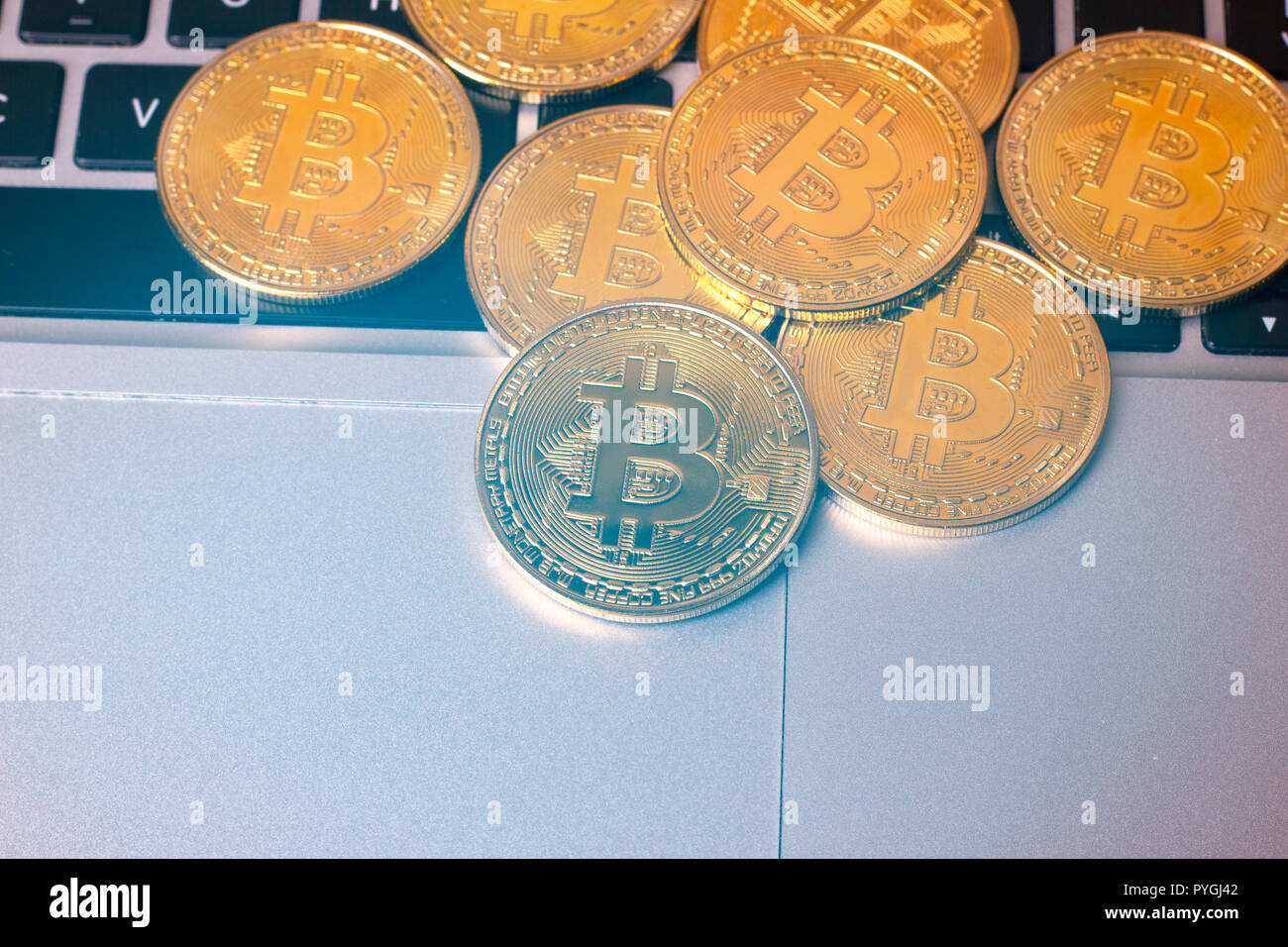 A stack of golden bitcoin coin on a silver keyboard of laptop. Virtual ...