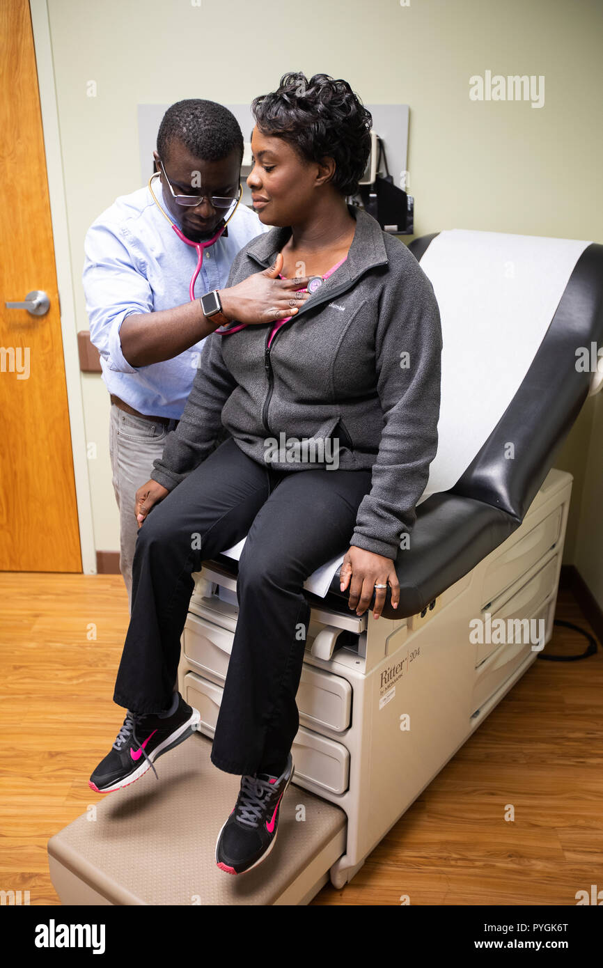 African-American doctor checks patient's heart and lungs with ...