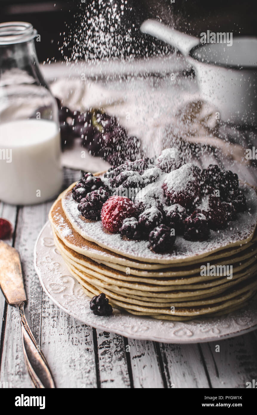 Homemade crepes with frozen berries, topped sugar, rustic wood board ...