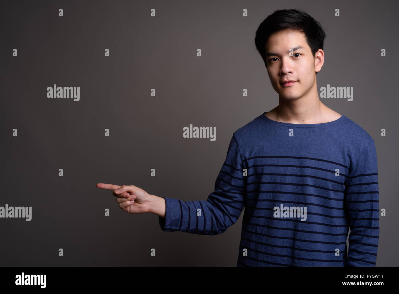 Asian man showing copy space with pointing finger Stock Photo - Alamy
