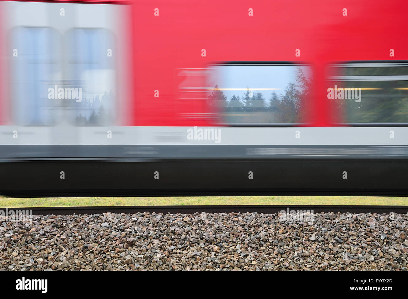 windows of fast passing train reflecting rural landscape with ...