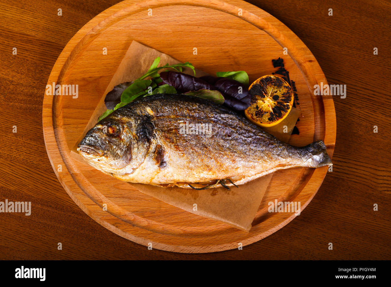 Grilled dorada with lemon over wooden background Stock Photo - Alamy