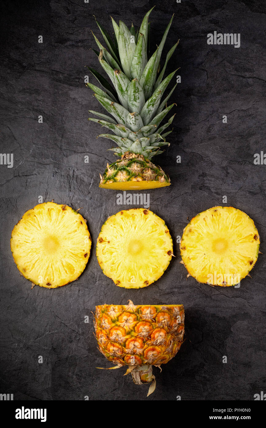 Fresh ripe pineapple cross sections on dark background, vertical ...