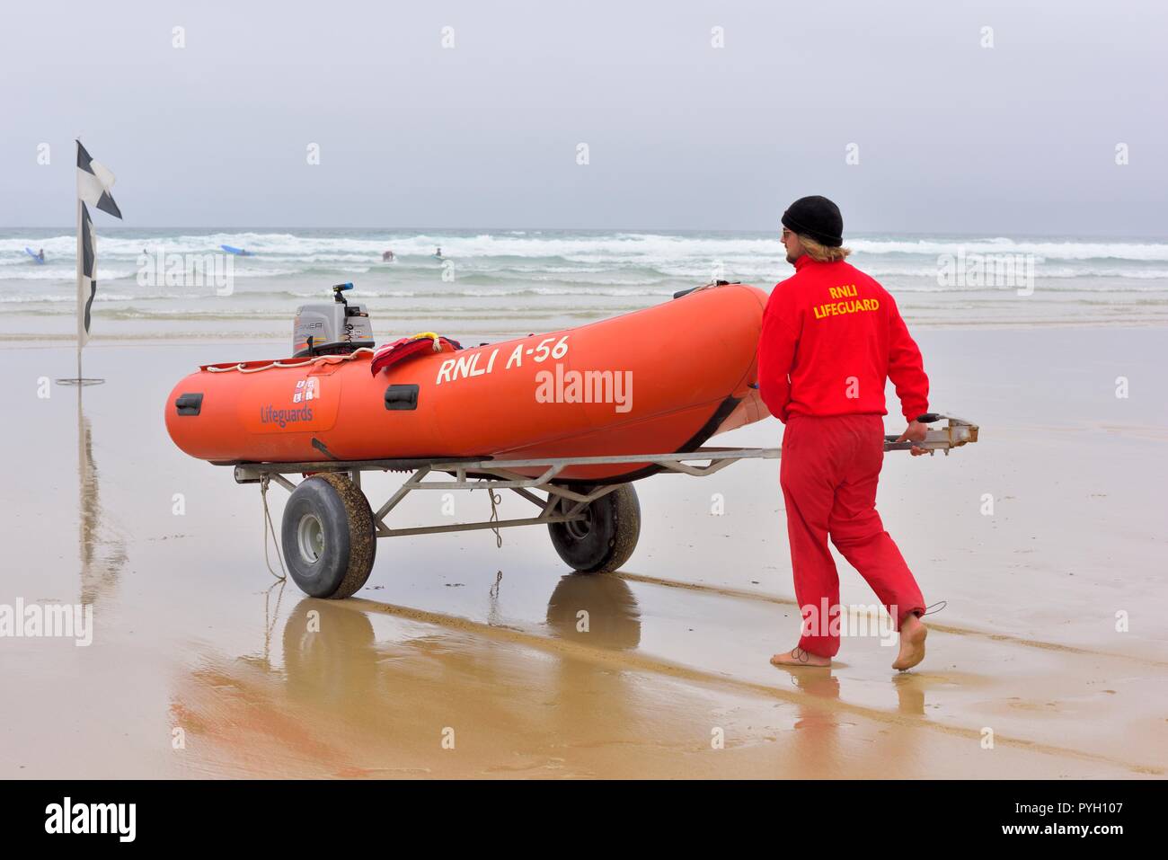 RNLI lifeguard moving an inflatable lifeboat into position on ...