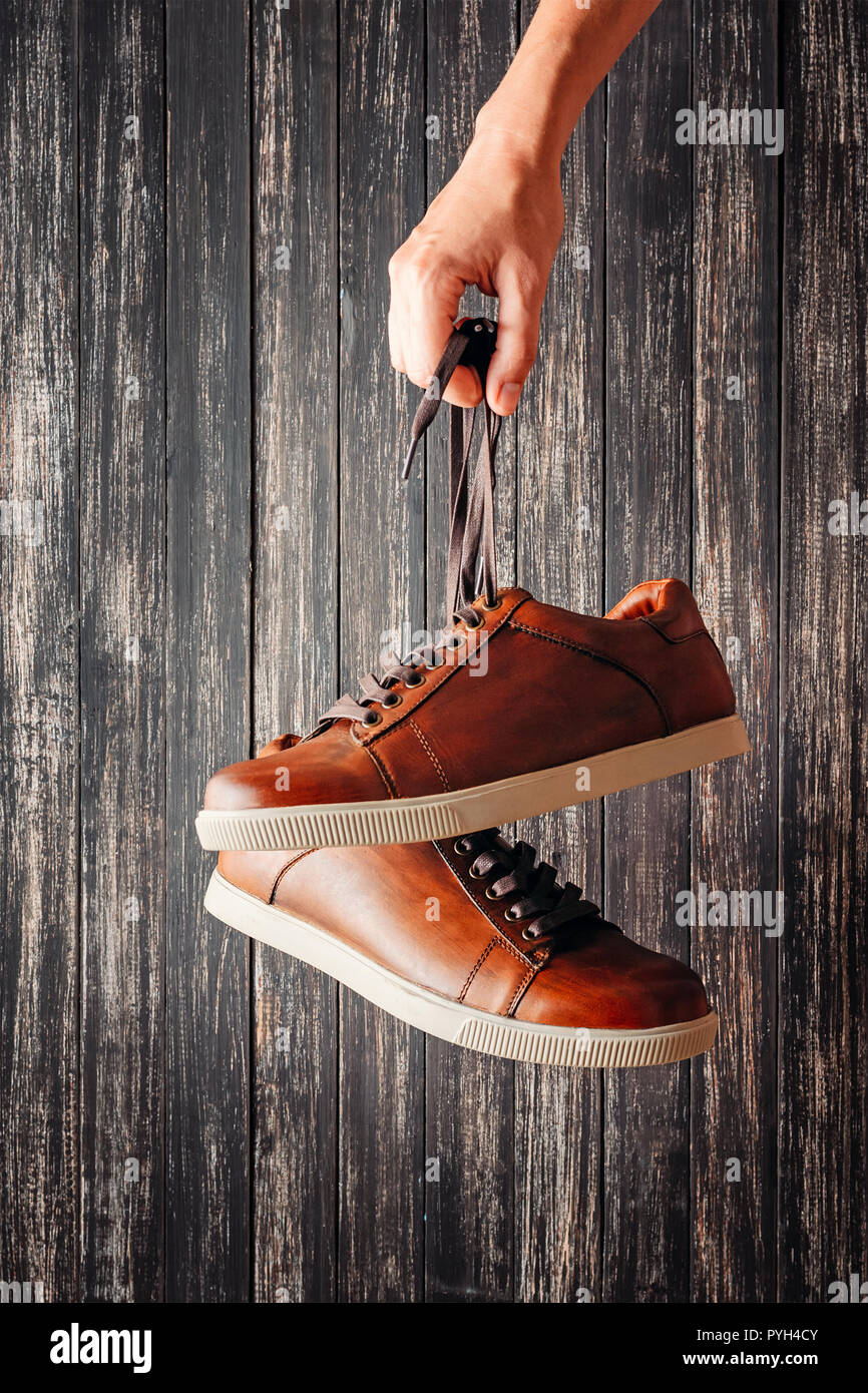 Hand holds for laces brown leather men's shoes on dark background Stock ...