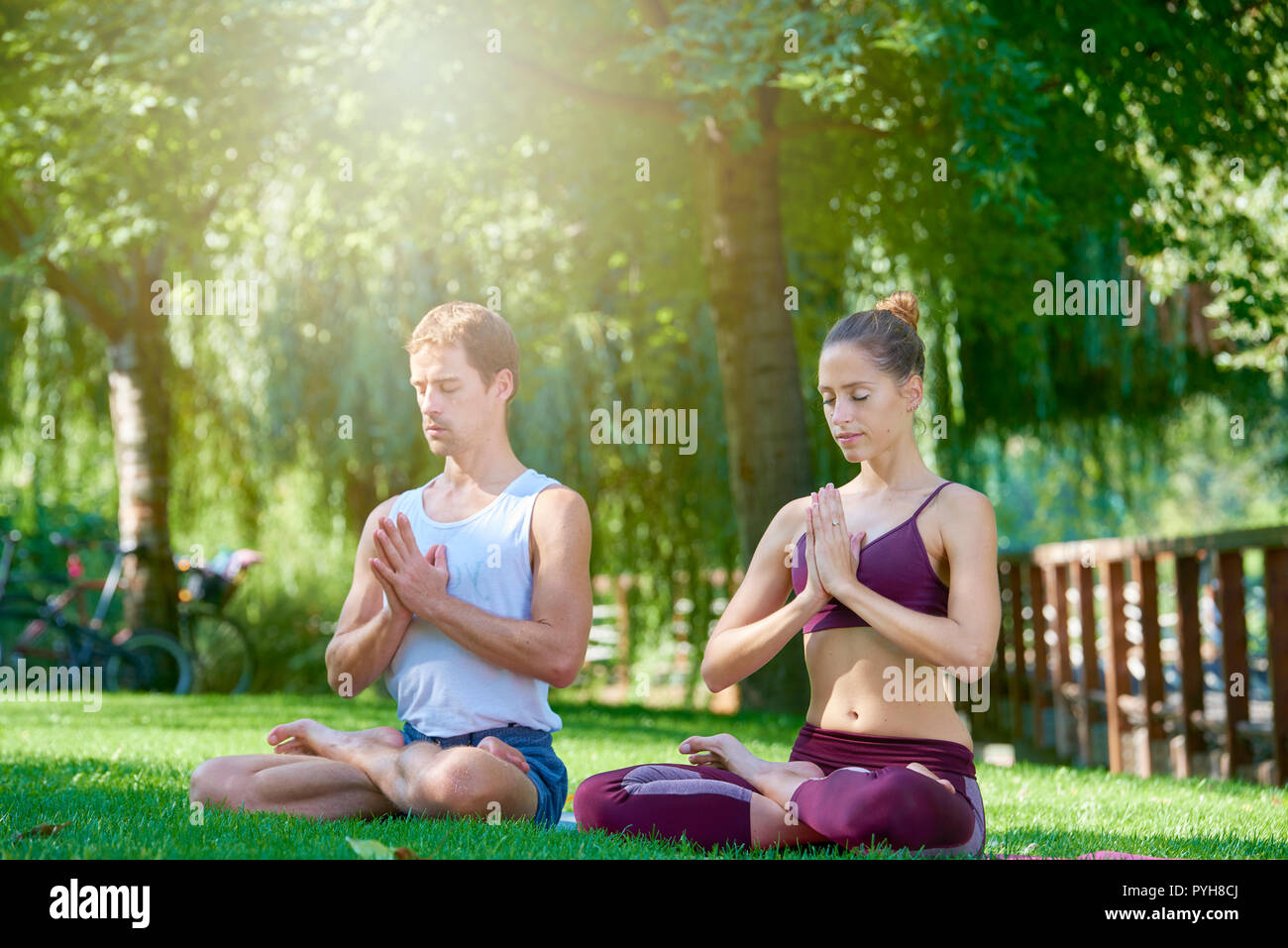 Full length shot of young man and woman training yoga together in the ...