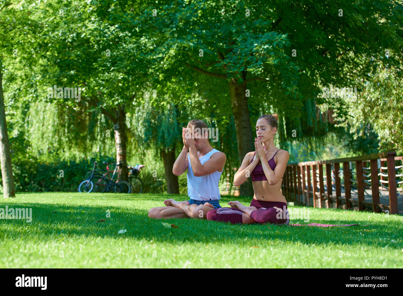 Full length shot of young man and woman training yoga together in the ...