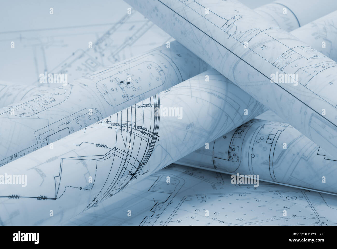 Rolled architectural plans lying on drawing board. Picture in blue tone ...