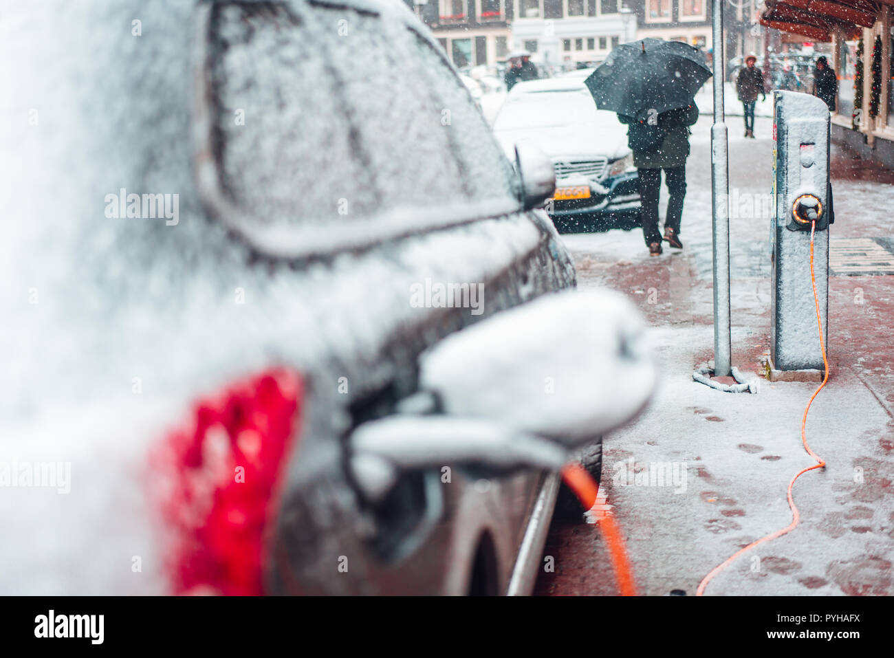 Electric car plug charging in the winter Stock Photo - Alamy