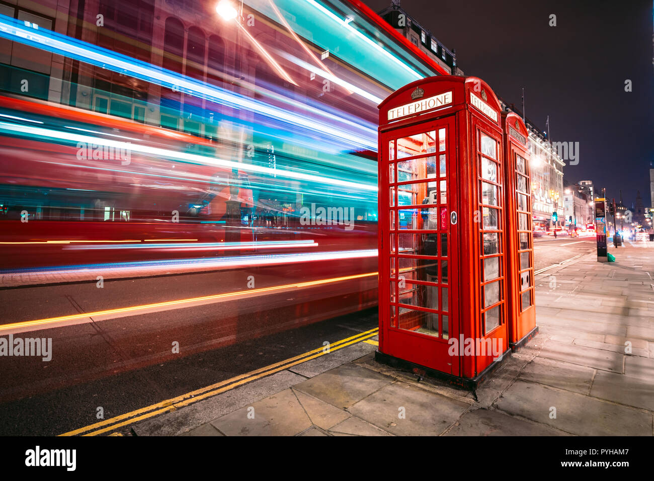 Light trails of a double decker bus next to the iconic telephone booth ...
