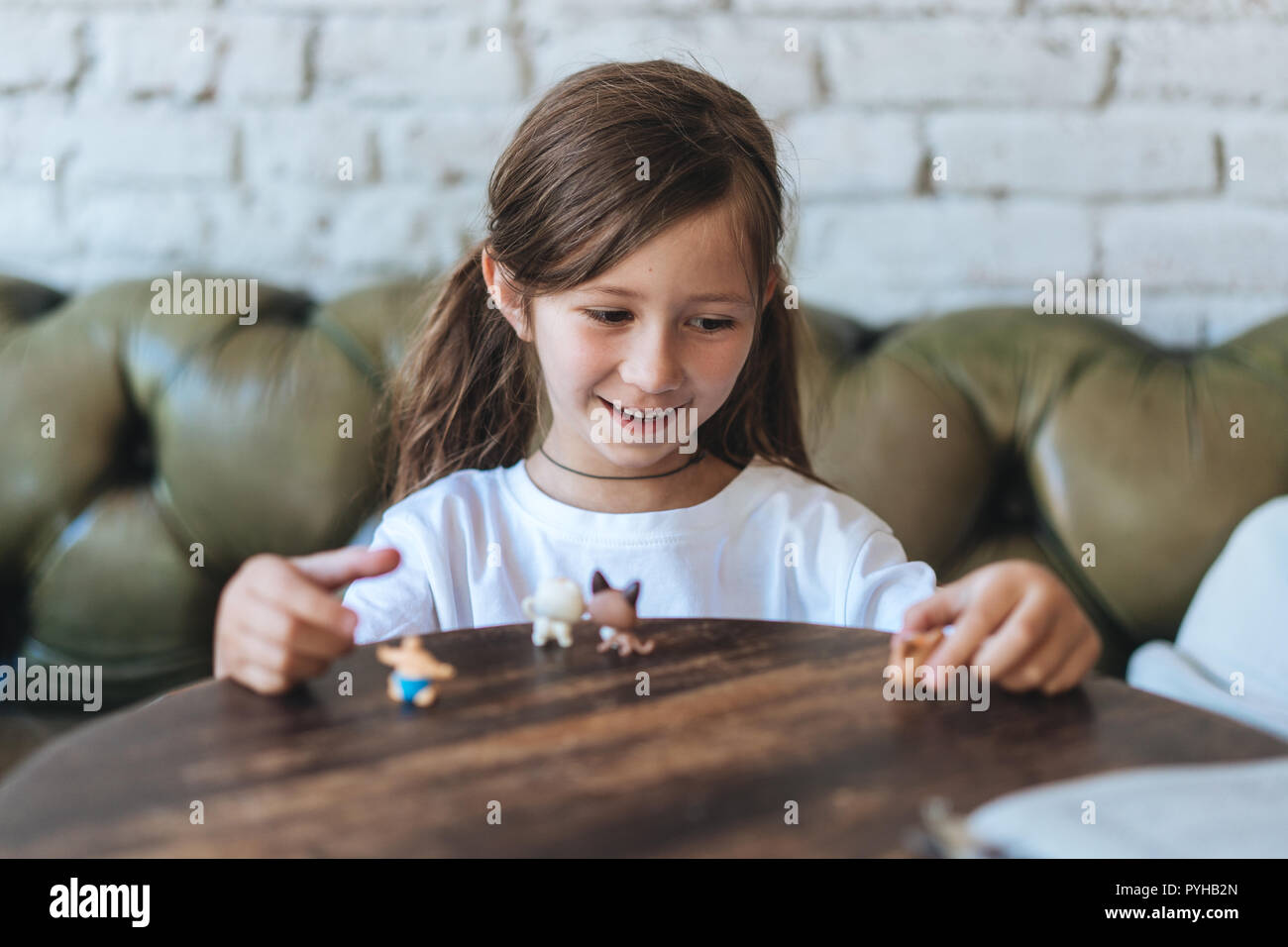 Girl playing with small figures sitting on soft Stock Photo - Alamy