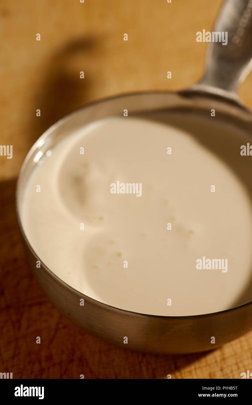 about 3/4 of a cup of American heavy cream in a steel measuring cup ...