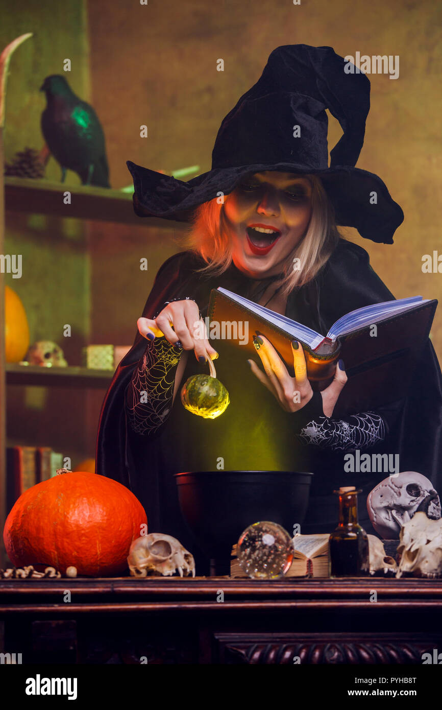 Image of blonde witch reading spell with pumpkin in hands Stock Photo ...