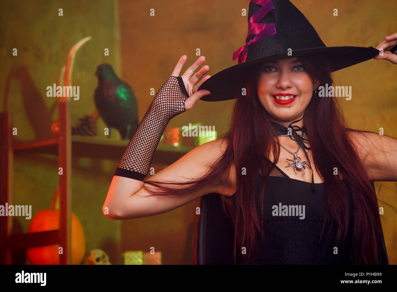 Image of witch in black dress and hat in magic room Stock Photo - Alamy