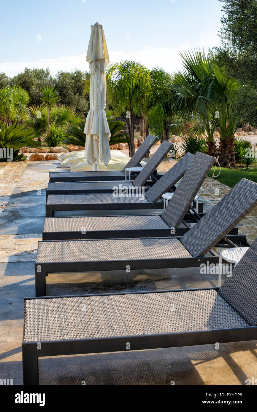 Modern sunbeds and parasol near the swimming pool Stock Photo - Alamy