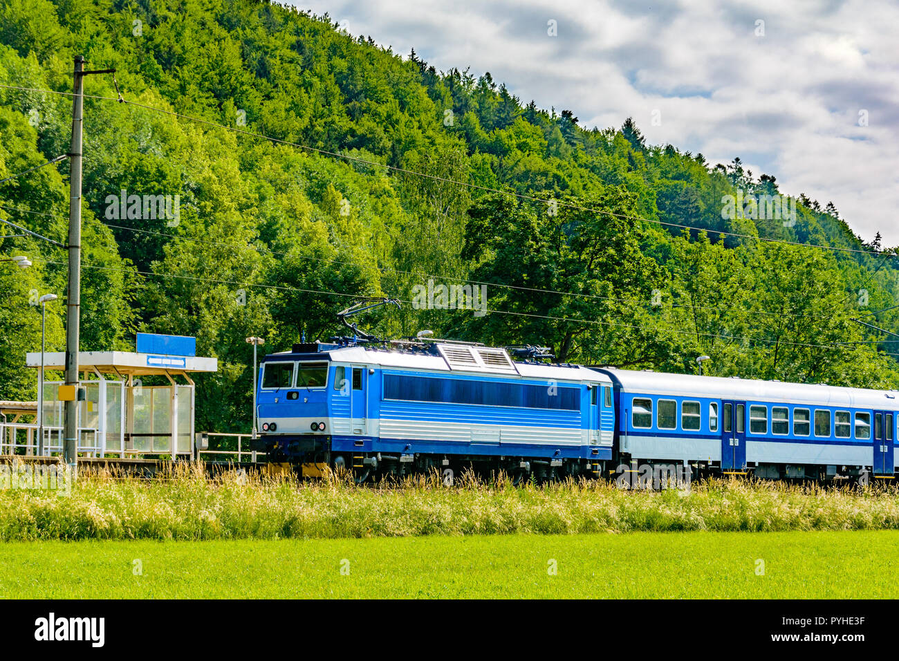 A blue electric locomotive passing the Czech countryside. A train ...