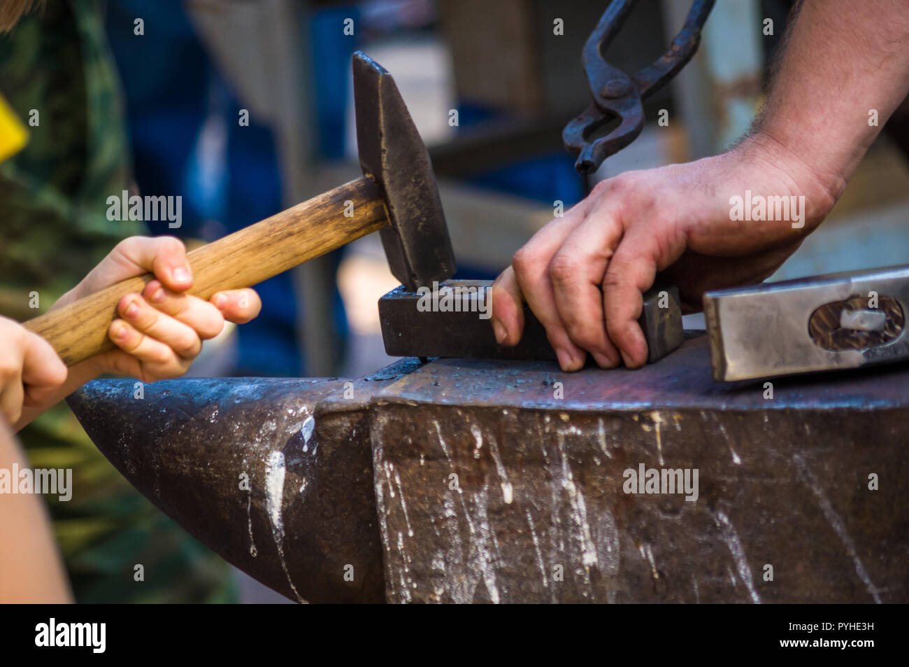 blacksmith performs the forging of hot glowing metal on the anvil ...
