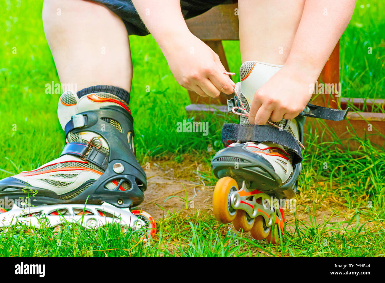 The skater binds the roller skates on the bench. Closeup inline skates ...