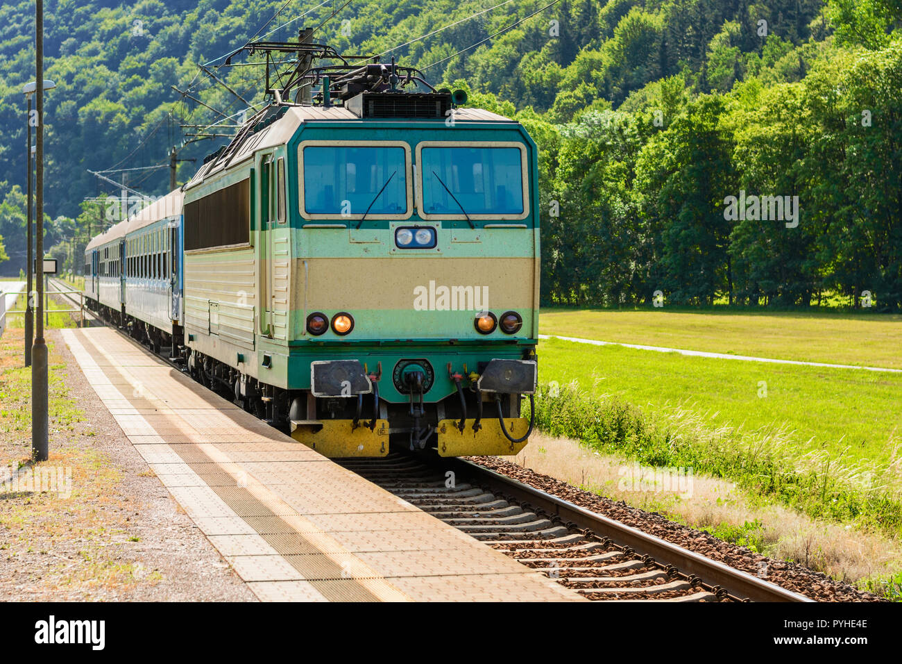 A green electric locomotive passing the Czech countryside. A train ...
