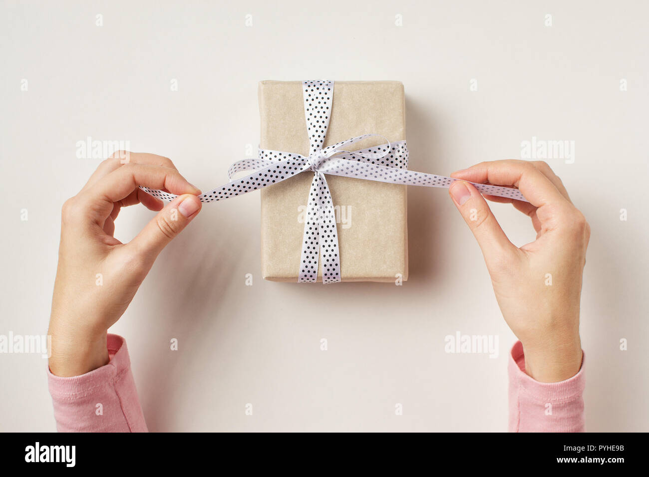 woman hands untie bow on gift box on white background, top view Stock ...