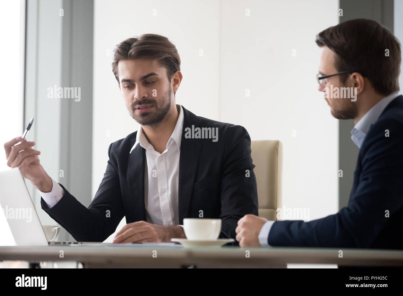 Two men discuss business project looking at laptop screen Stock Photo ...