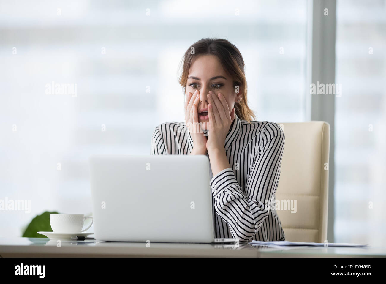 Shocked young woman looking at laptop screen Stock Photo - Alamy