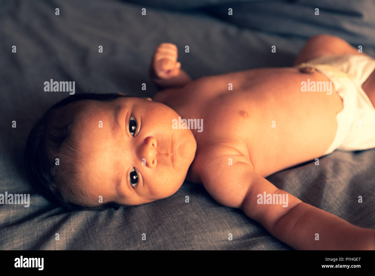 A baby on a bed looking at the camera, wide angle Stock Photo - Alamy