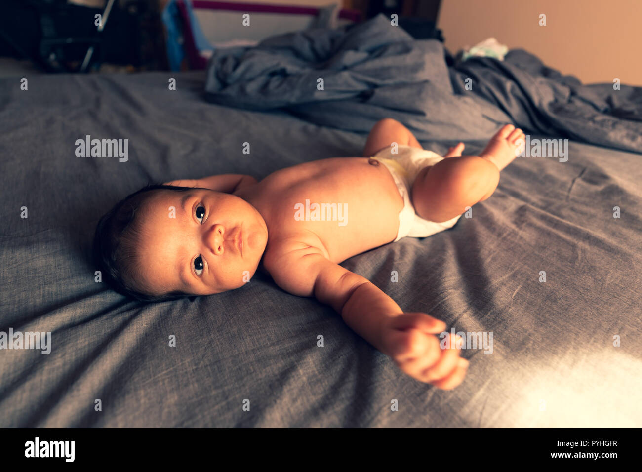 A baby on a bed looking at the camera, wide angle Stock Photo - Alamy