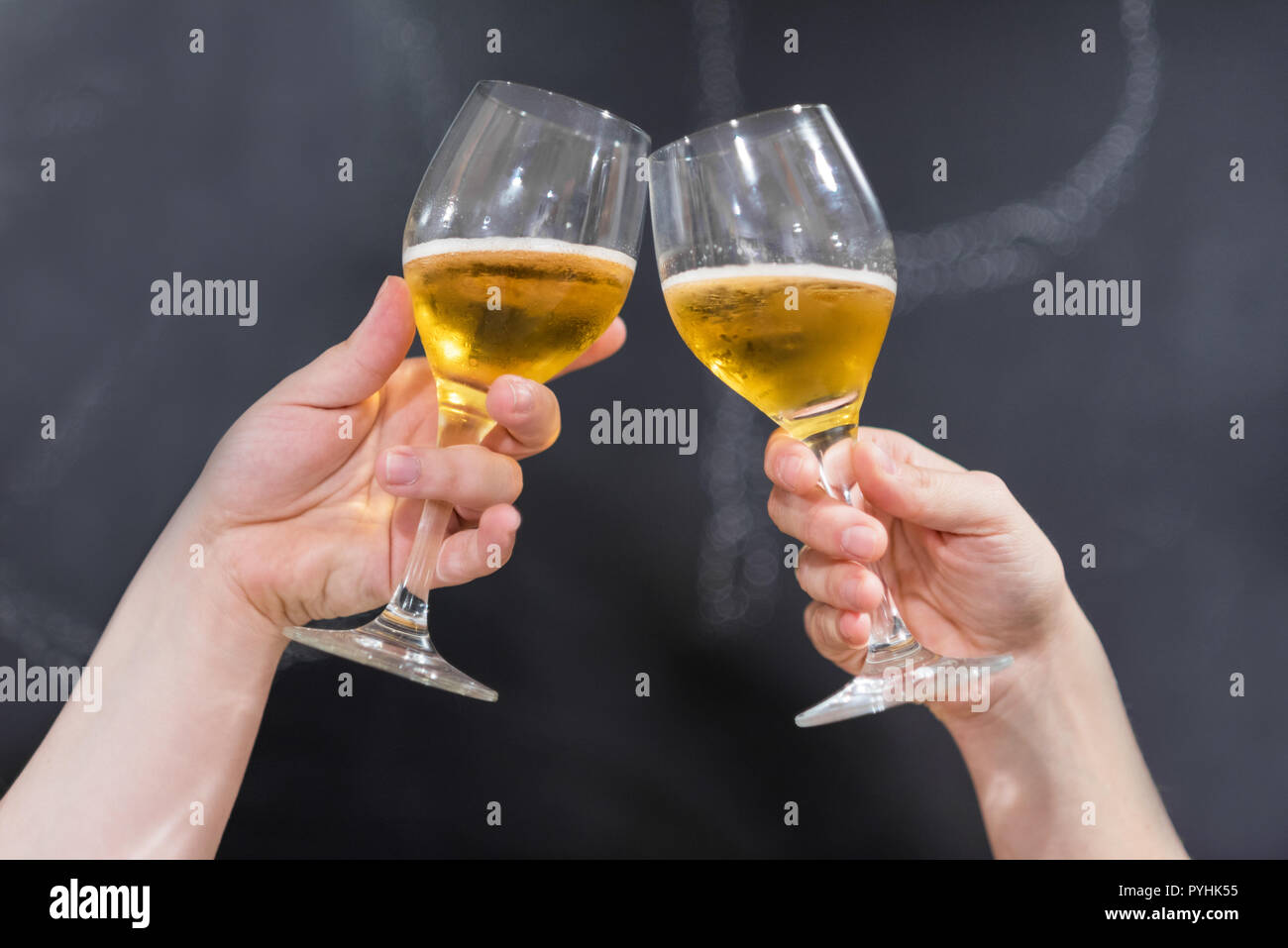 Two friends toasting with glasses of beer at the pub. Blackboard ...