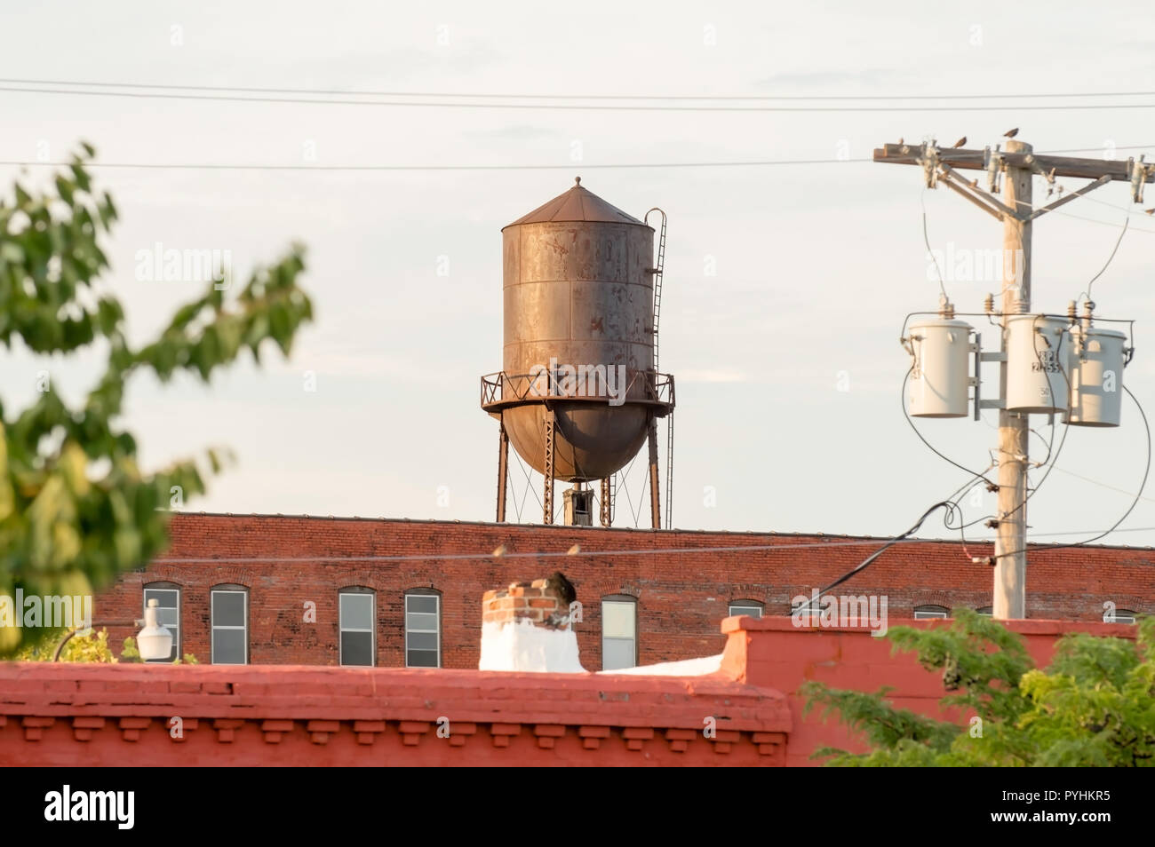 A rusty water tower rising above an old industrial brick building in St ...