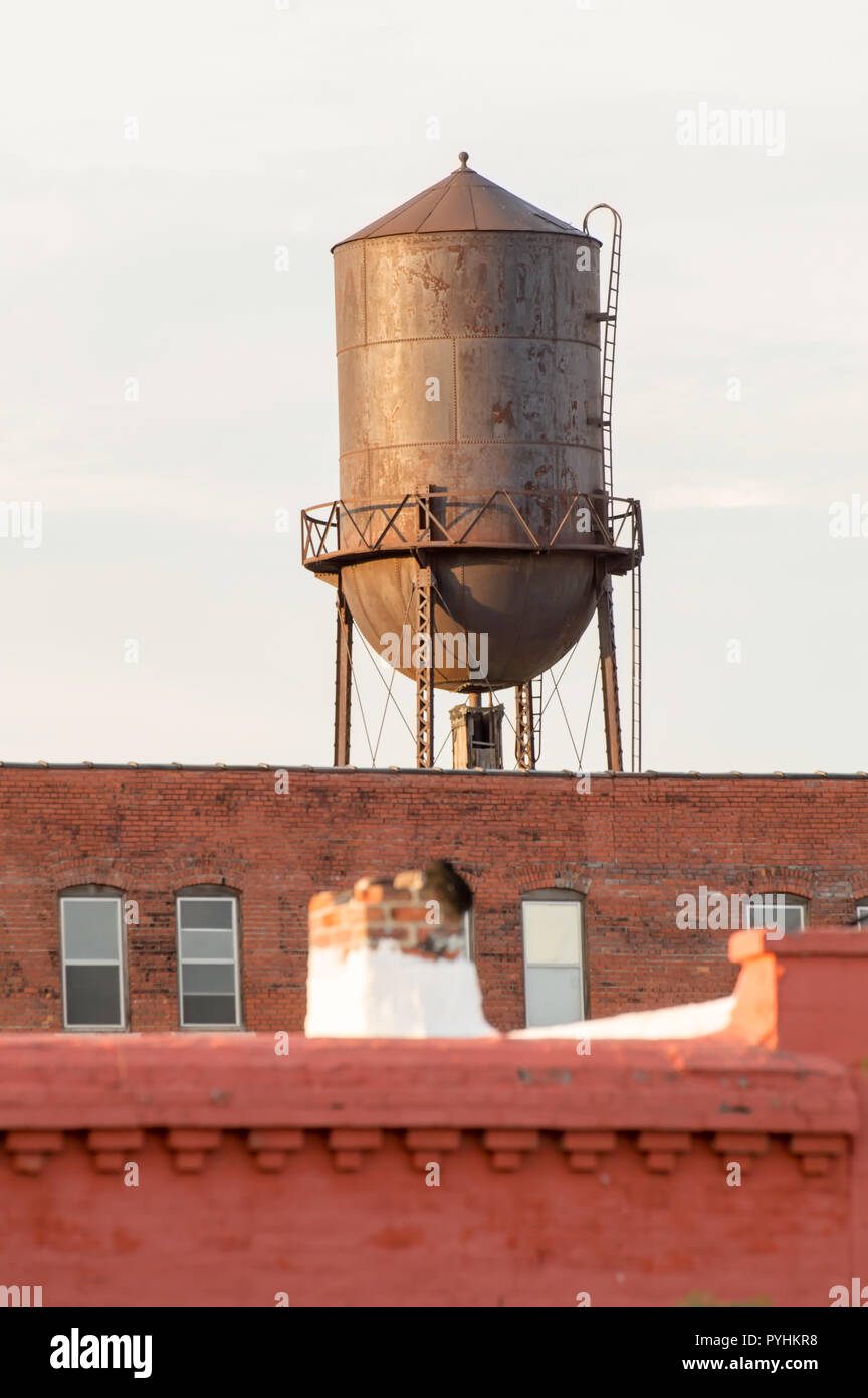 A rusty water tower rising above an old industrial brick building in St ...